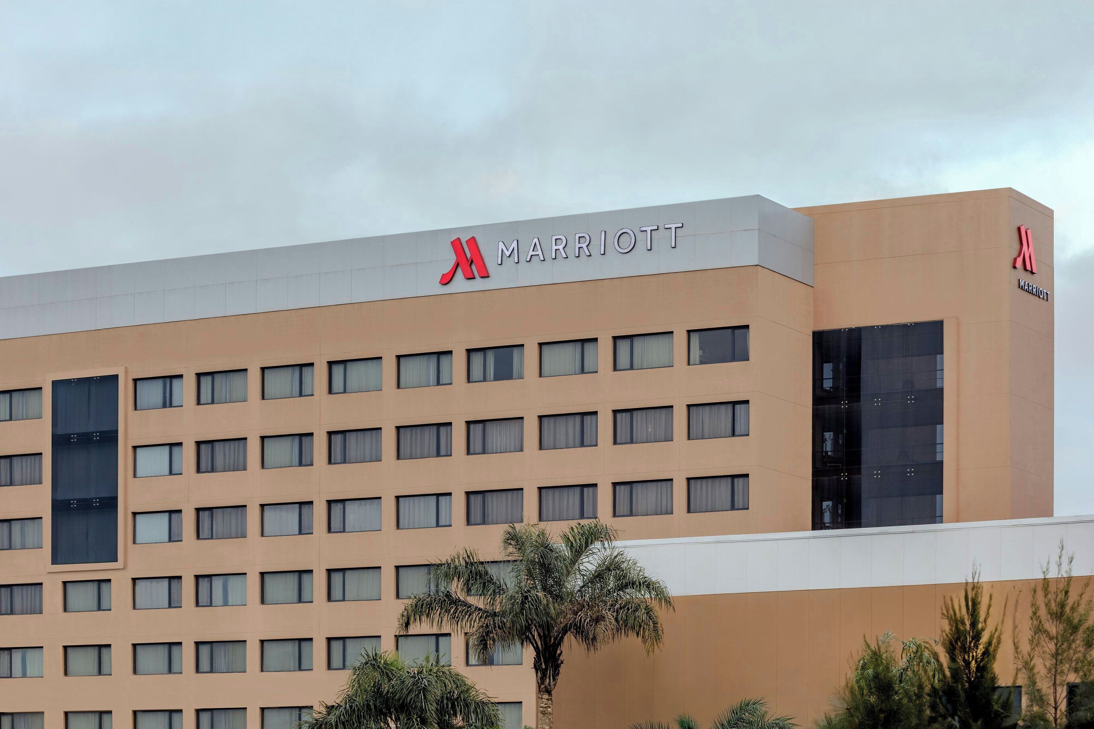Um edifício de vários andares com o logotipo da Marriott, apresentando um design arquitetônico moderno com telhado plano e várias janelas.