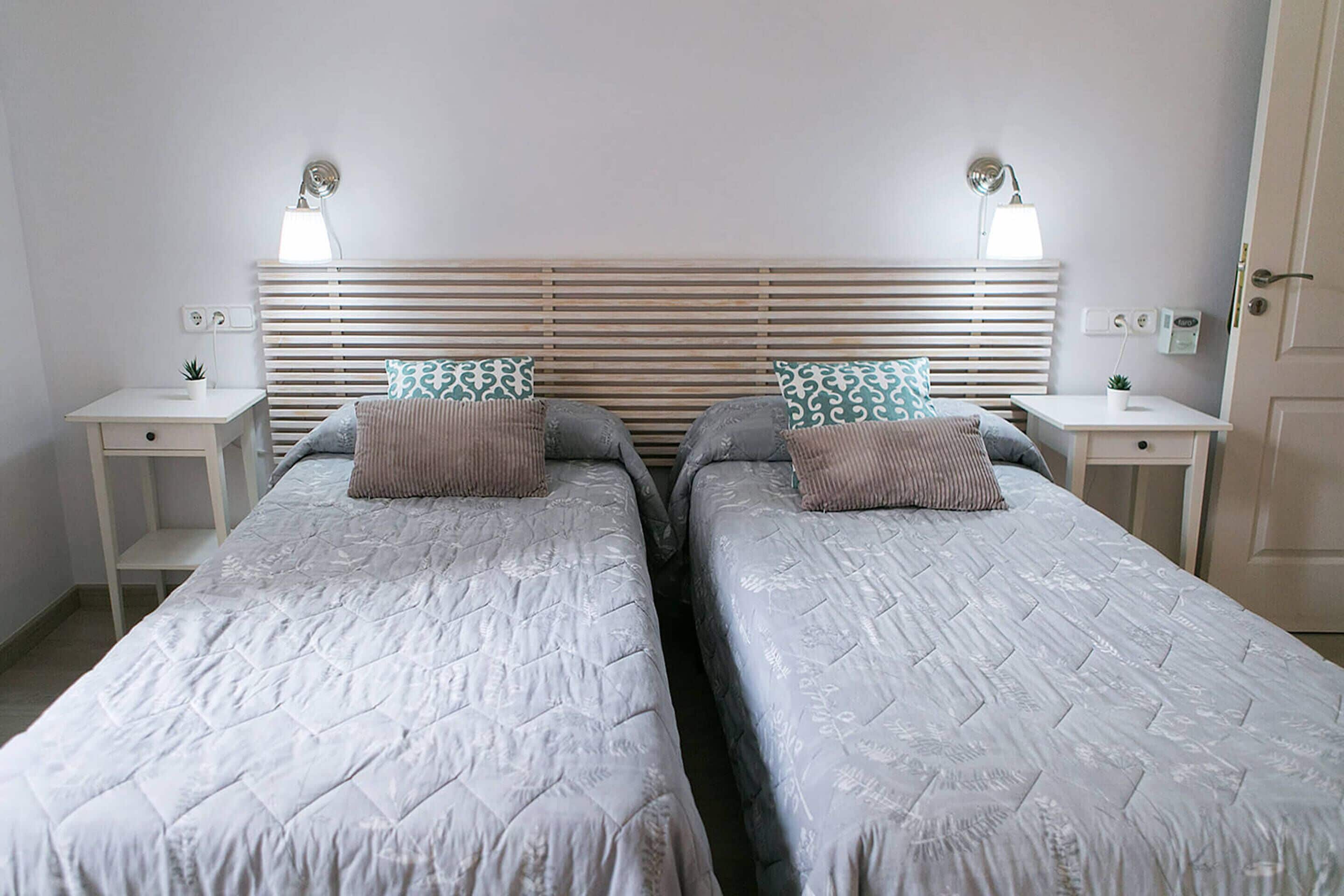 Quarto duplo com duas camas, cada uma com cabeceira, mesas de cabeceira e luminárias.
