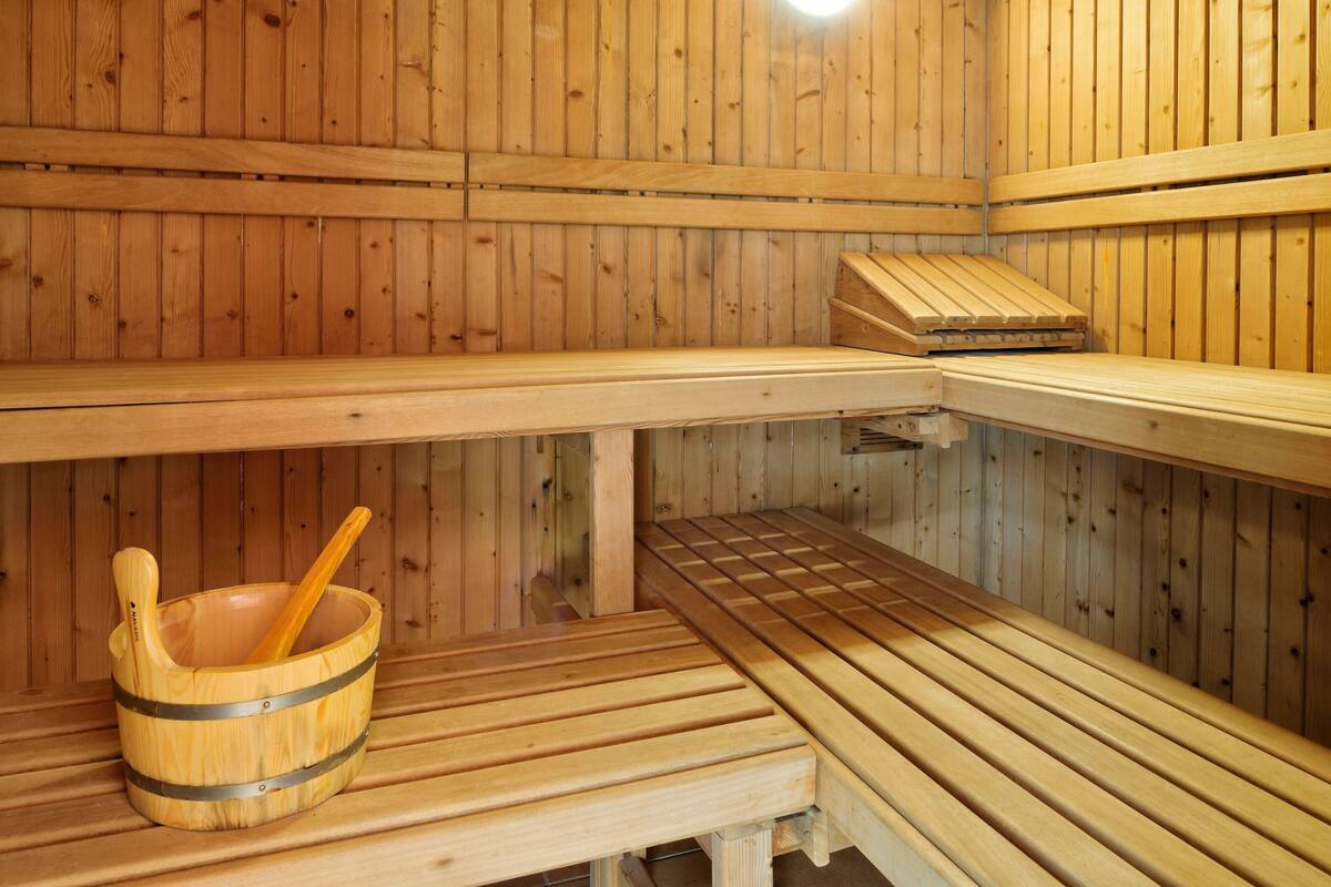 Uma sauna com bancos de madeira e um balde de madeira com uma concha.