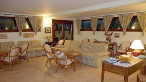 Uma sala de estar acolhedora com um sofá, cadeiras de madeira, uma mesa de jantar e um abajur.