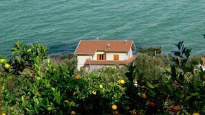 Uma casa com telhado vermelho, localizada à beira da água.