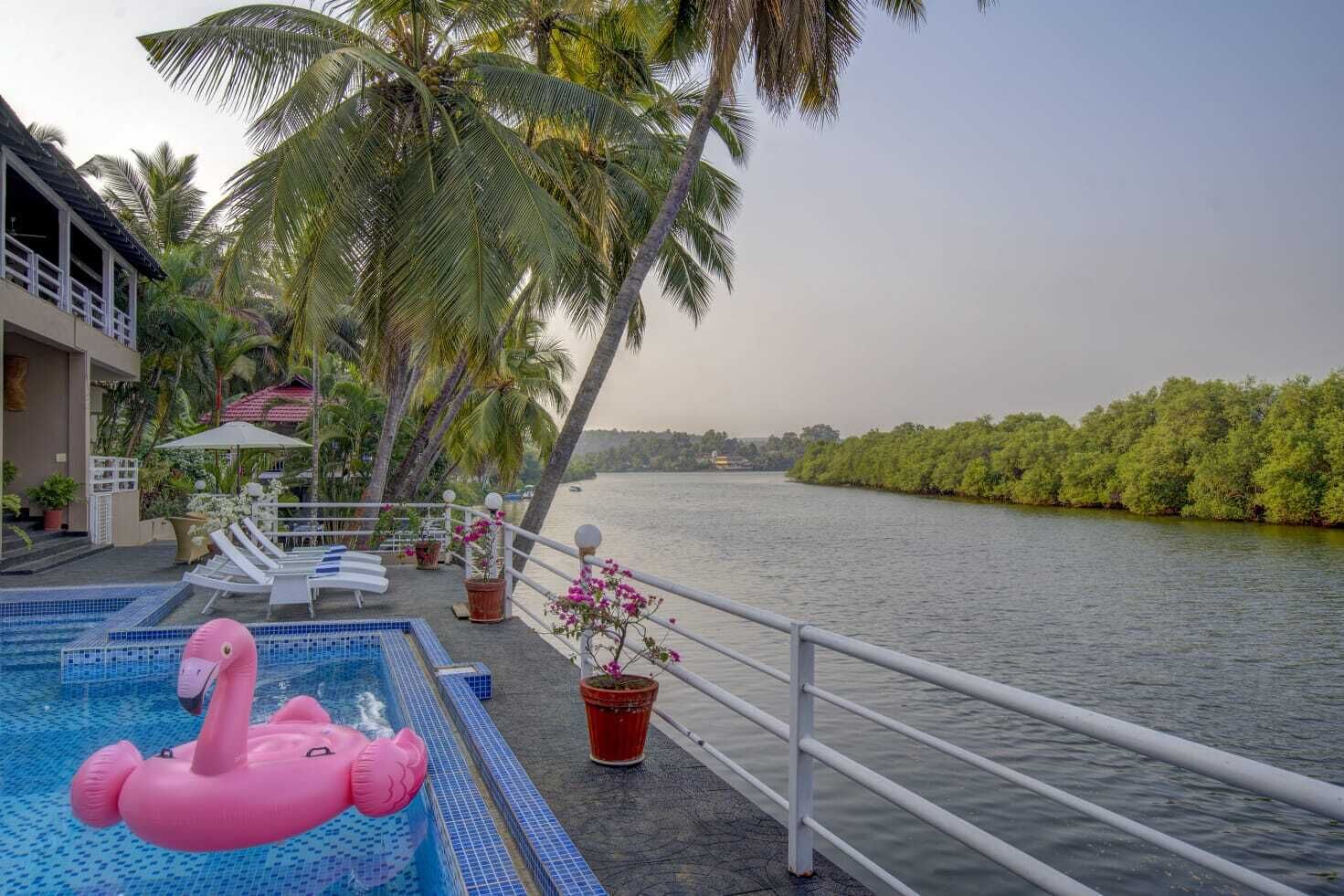 Uma piscina com um flutuador de flamingo rosa, cadeiras de descanso e plantas em vasos.