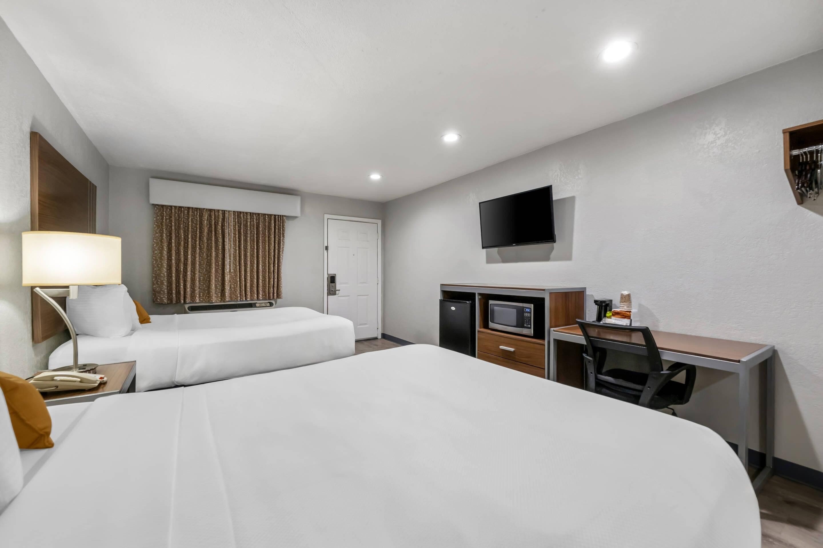 Quarto de hotel com duas camas, uma escrivaninha, televisão, micro-ondas e máquina de café.