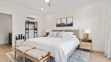 Quarto moderno com uma cama grande, piso de madeira e um ventilador de teto.
