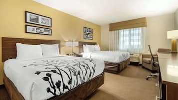 Quarto de hotel com duas camas, uma escrivaninha, uma cadeira e uma janela com cortinas.
