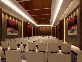Uma sala de conferências com fileiras de cadeiras brancas, painéis de madeira e quadros nas paredes.