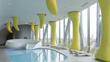 Uma área interna de piscina moderna com design arquitetônico único, apresentando uma piscina curvilínea e vários espreguiçadeiras.