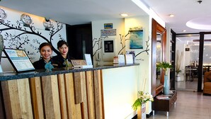 Uma receção com bancada de design em madeira, um relógio digital e uma placa de identificação da receção.