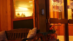 Um banco de madeira com almofadas, uma pequena mesa com uma vela e uma placa com a inscrição 'Hotel Post'.