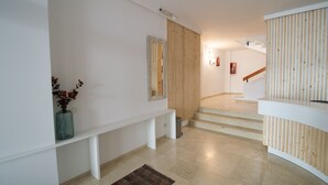 Um interior moderno com escada, parede de painéis de madeira e balcão de recepção branco.