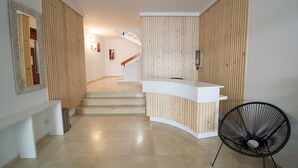 Um interior moderno com um balcão de recepção, uma escada e uma cadeira preta.