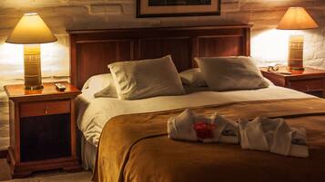 Quarto de hotel aconchegante com uma cama grande, duas luminárias de cabeceira, um quadro na parede e um tapete decorativo.