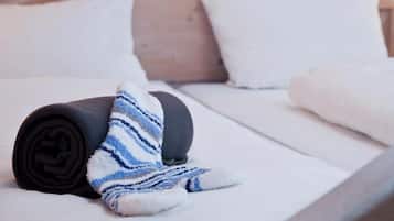 Cama bem arrumada com uma toalha enrolada e uma meia listrada.