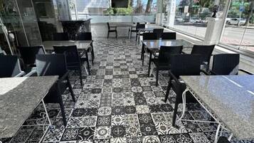 Um café ao ar livre com piso estampado, mesas e cadeiras.