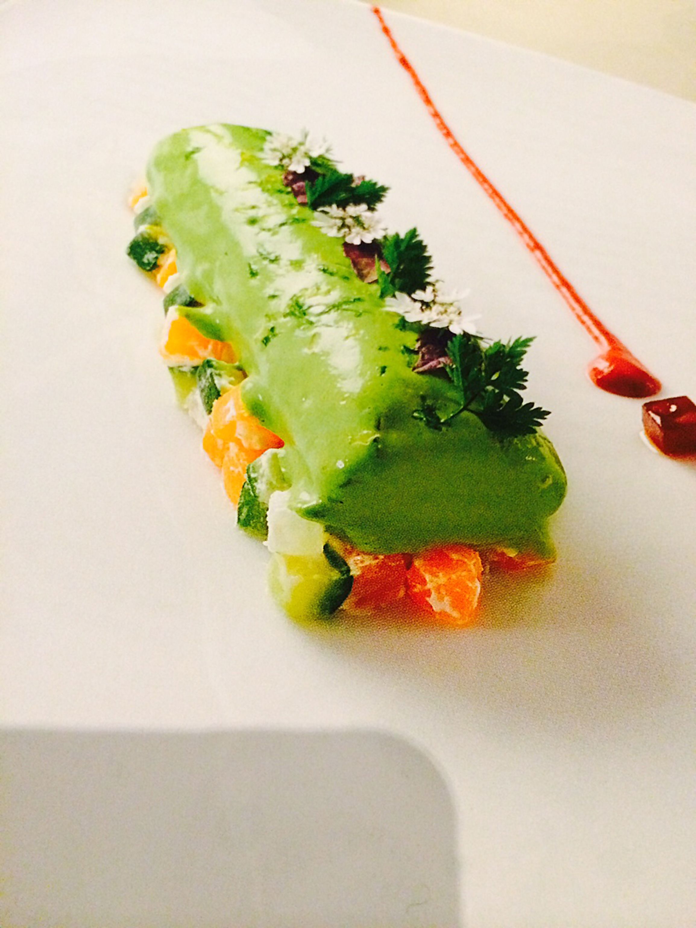 Um prato com molho verde, segmentos de laranja e molho vermelho.