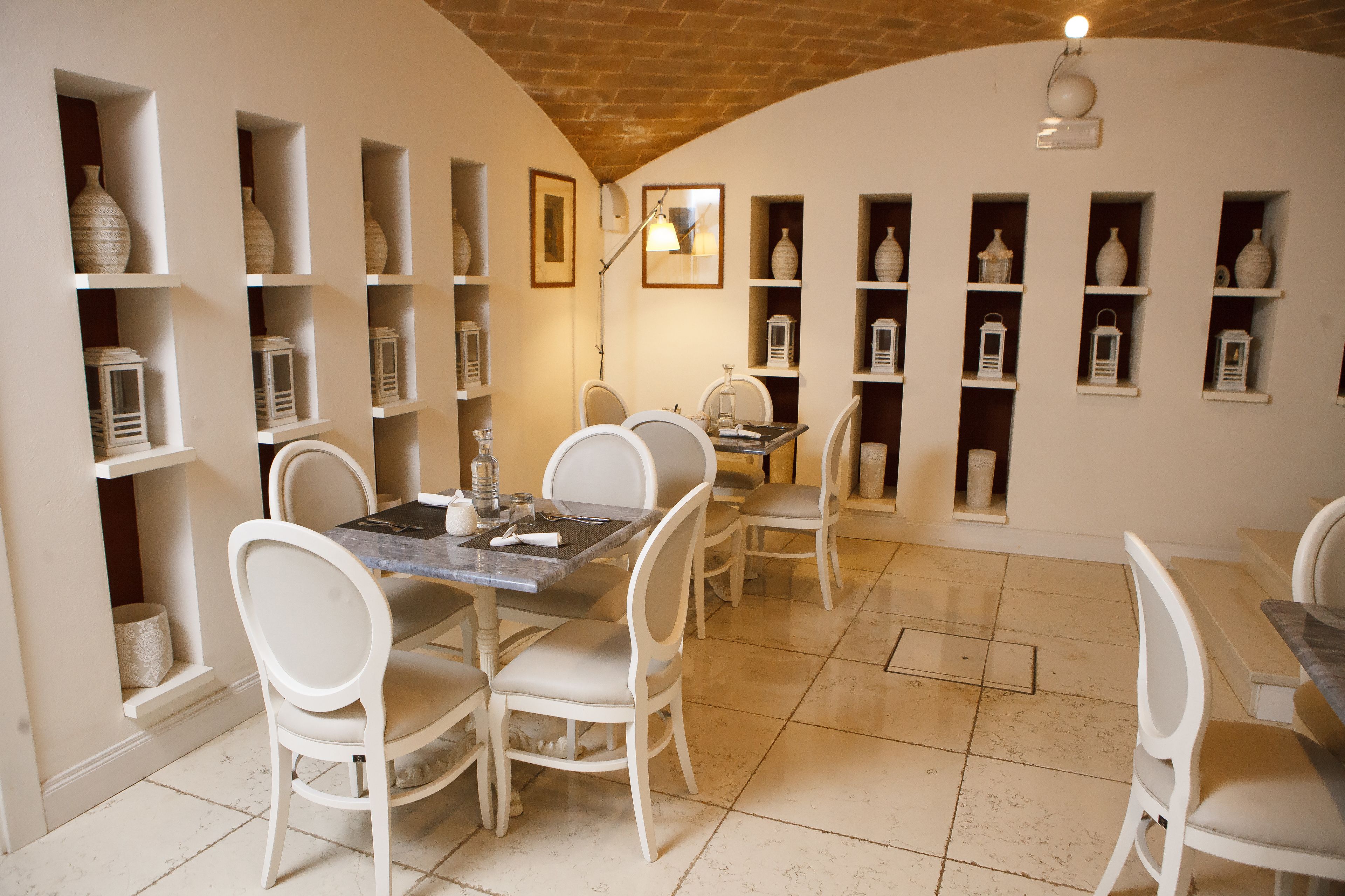 Uma área de refeições com mesa e cadeiras, rodeada por estantes com objetos decorativos.