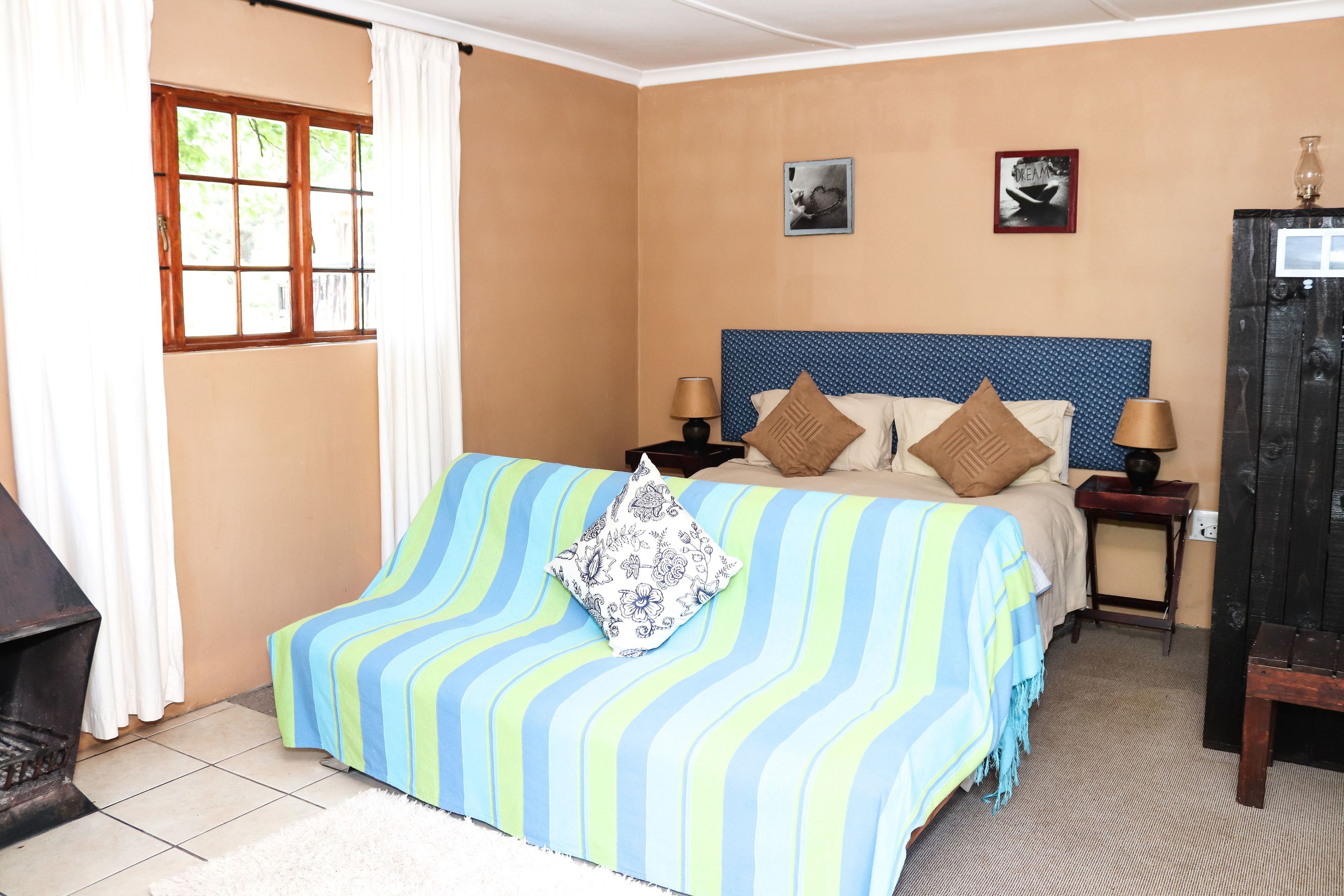 Quarto de hotel com uma cama, duas mesas de cabeceira, um penteado e uma janela com cortinas.