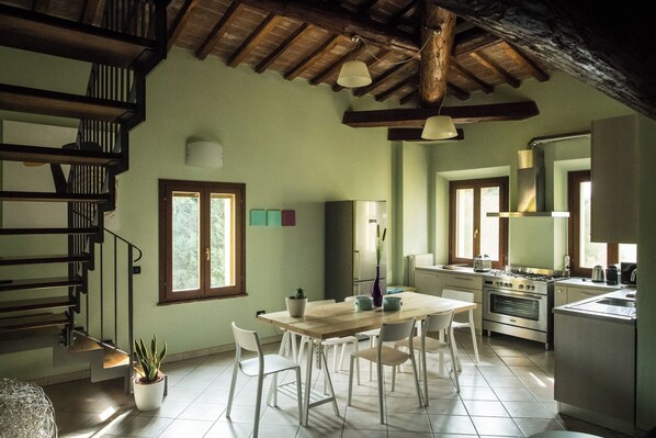 Uma cozinha espaçosa com mesa e cadeiras de madeira, forno embutido e uma grande janela que oferece muita luz natural.