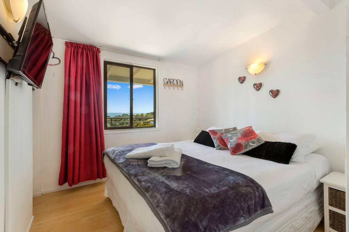 Um quarto com uma cama, uma janela com vista, uma televisão e um aviso que diz "GARDEN".
