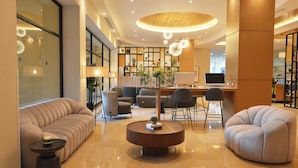Um hall moderno com sofá, poltronas, mesa de centro e espaço de trabalho.