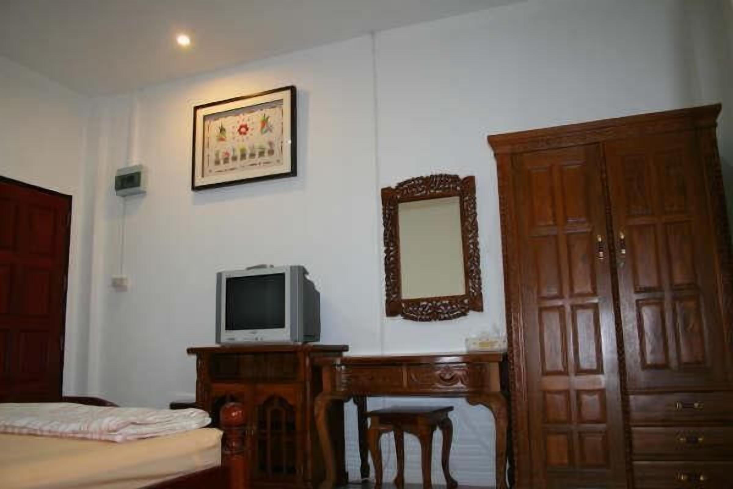Quarto com cama, cómoda de madeira, televisão, espelho e um quadro na parede.