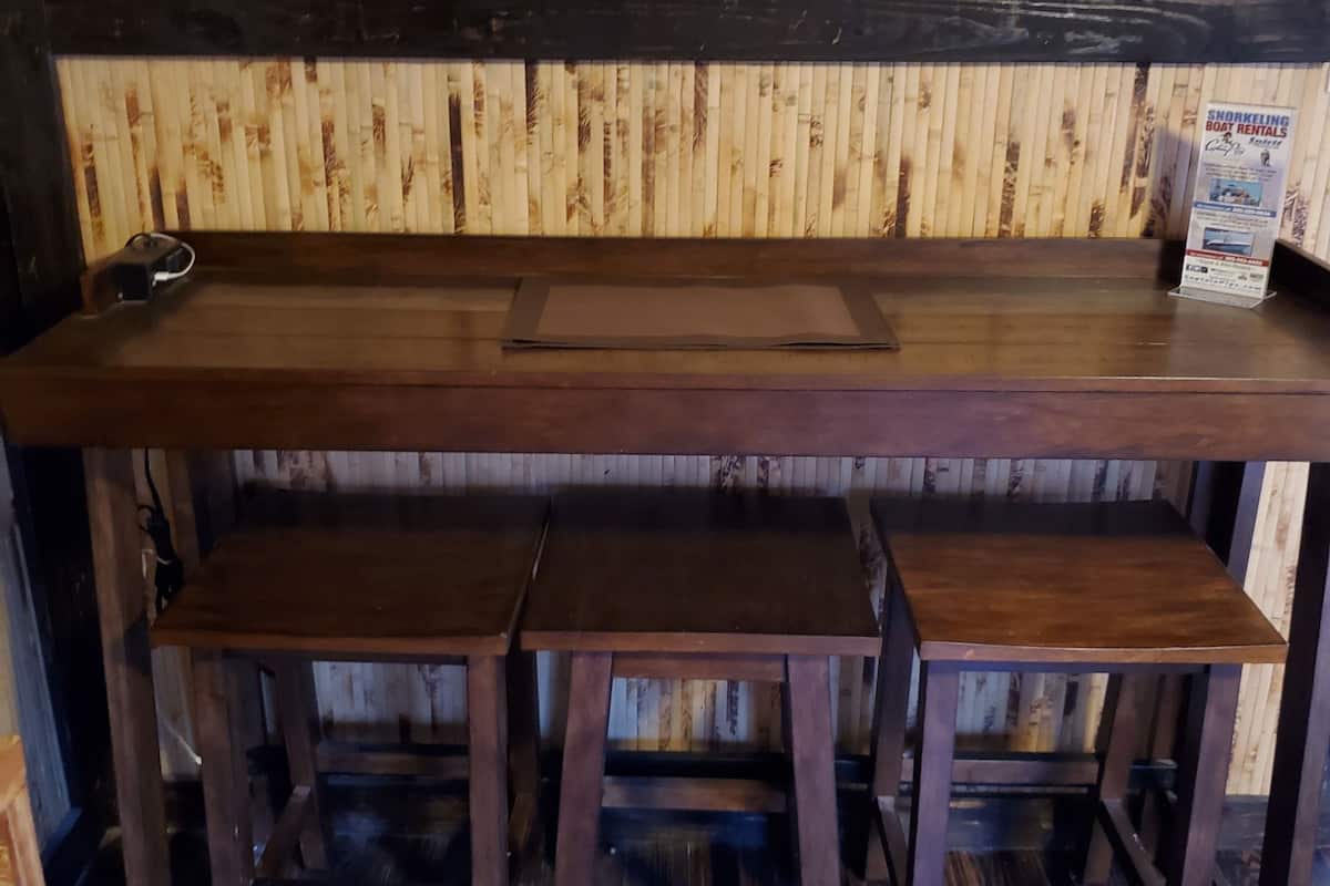Uma área de bar com balcão longo e três banquetas.