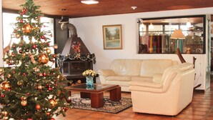 Uma sala de estar aconchegante com uma árvore de Natal, lareira, sofá e mesa de centro.