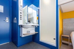 Uma casa de banho com parede azul, pia branca, espelho e porta-toalhas.