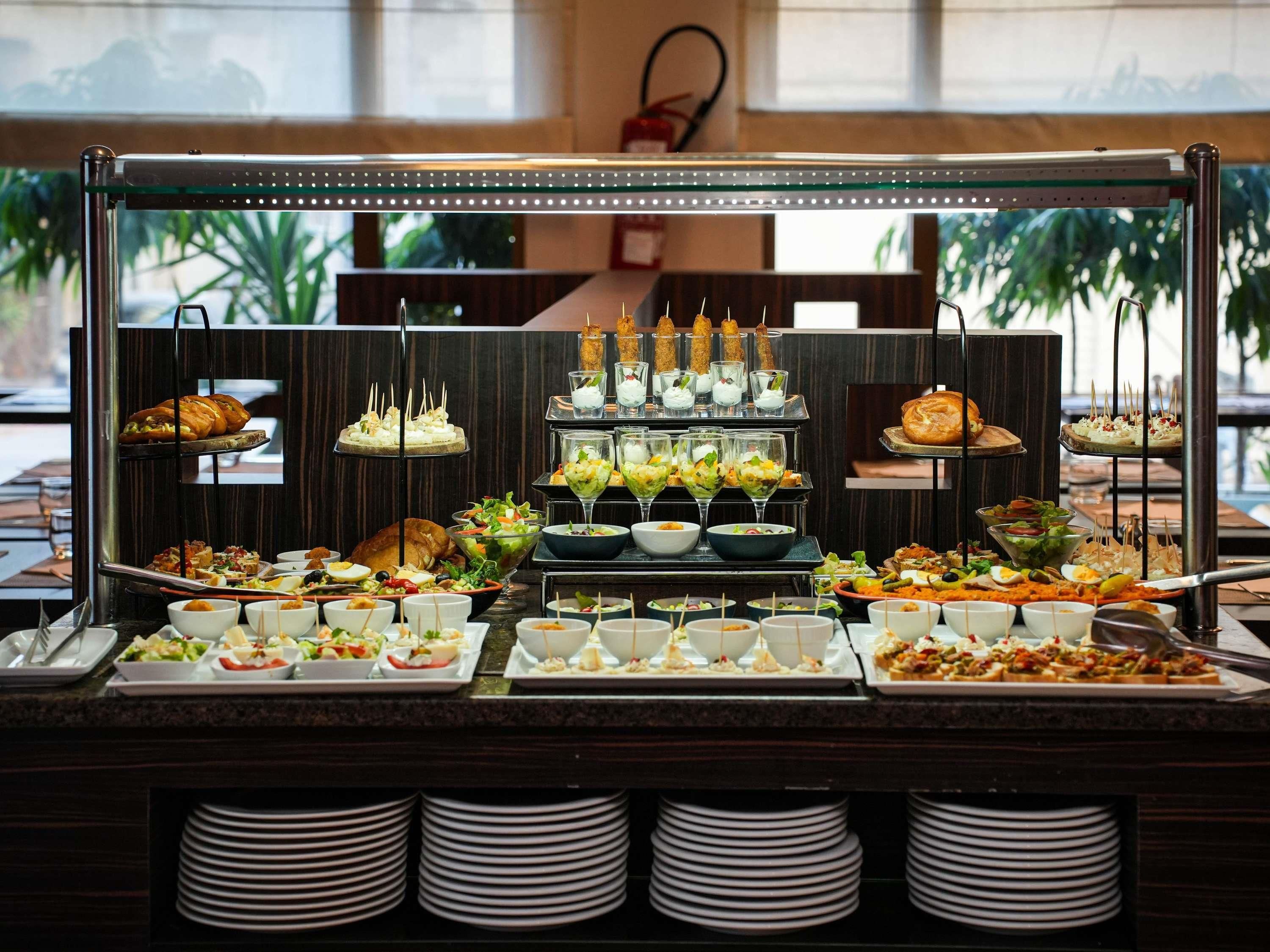 Um buffet com diversos alimentos e bebidas, dispostos em vários níveis e pratos.