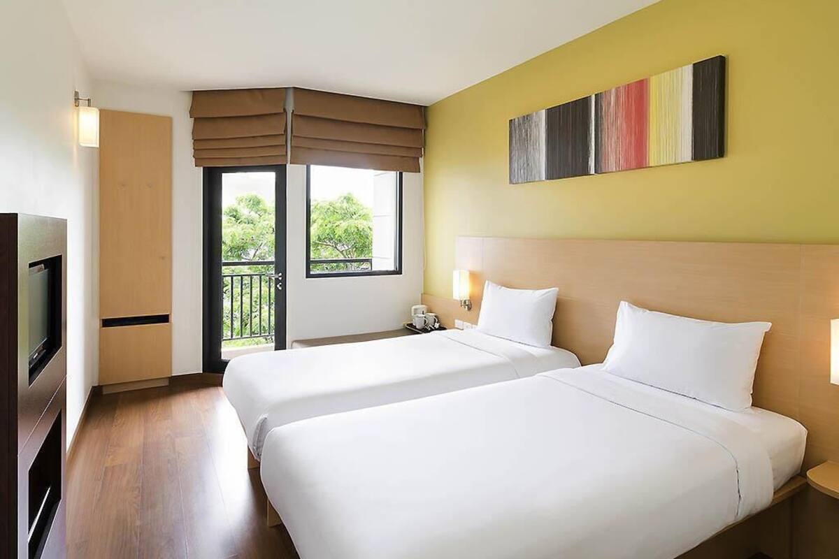 Quarto de hotel com duas camas, televisão, varanda e um quadro na parede.
