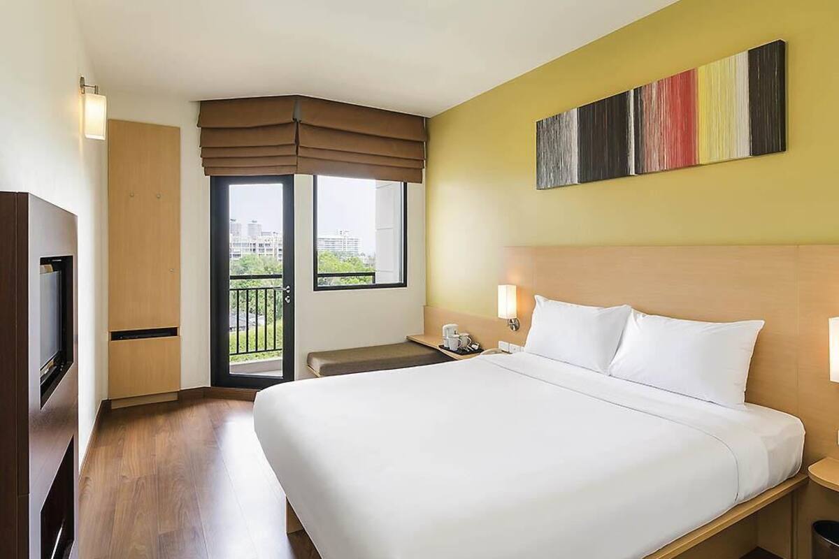 Quarto de hotel com uma cama grande, uma mesa, uma cadeira, televisão e varanda com vista.