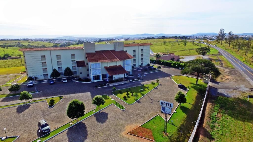 Hotel com um pátio central, vários espaços de estacionamento e vista para a paisagem circundante.