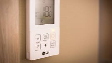 Um termostato branco da LG com visor digital mostrando 18°C, botões de controle de temperatura e controle de velocidade do ventilador.