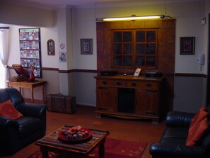 Uma sala de estar com lareira, uma mesa de centro com frutas, um sofá de couro e um armário de madeira.