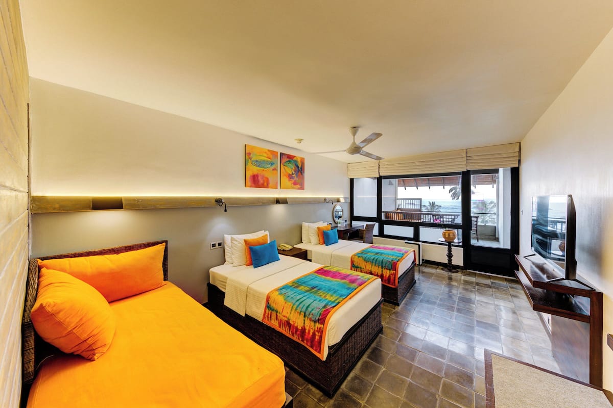 Quarto de hotel com duas camas, televisão e varanda com vista.