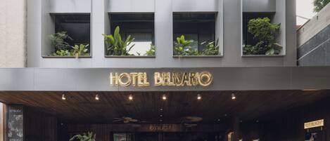 Entrada de um hotel com design moderno, exibindo uma placa com a inscrição 'HOTEL BELIZARDO'.