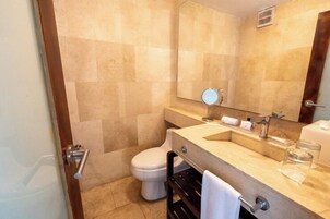 Casa de banho com sanita, lavatório, espelho e suporte para toalhas.