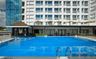 Um hotel moderno com piscina, área de estar ao ar livre e espaço coberto com guarda-sóis.
