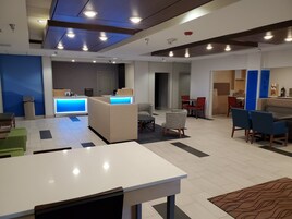 Um hall de hotel moderno com balcão de recepção, área de estar e espaço para refeições.