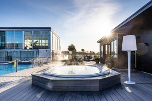 Uma área de piscina moderna ao ar livre, com hidromassagem, espreguiçadeiras e deck de madeira.