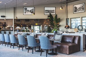 Uma área de bar moderna com assentos, balcão e grandes janelas.