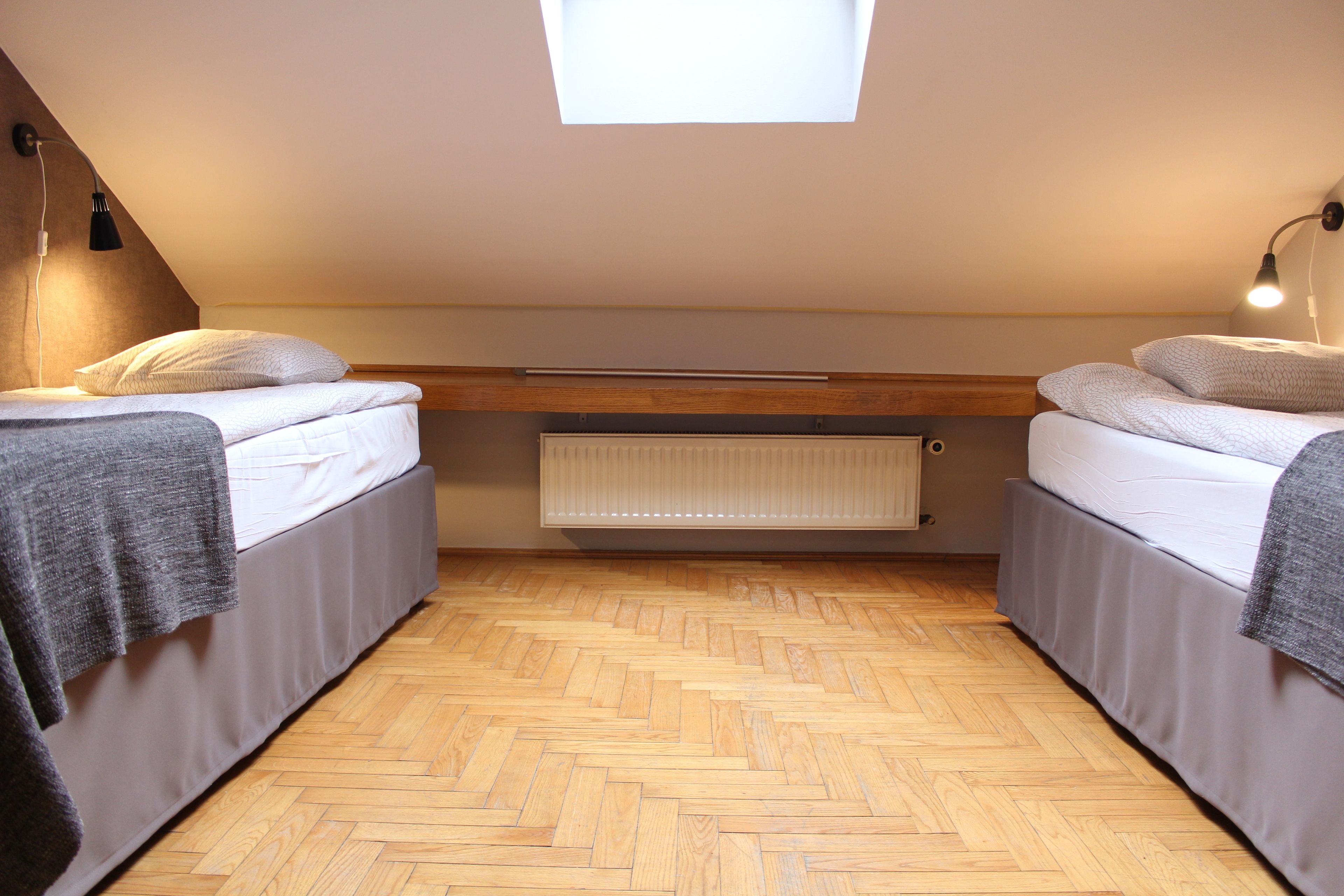 Quarto pequeno e acolhedor com duas camas, um claraboia e um radiador.