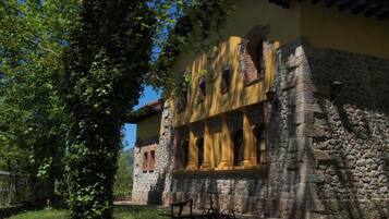 Um edifício histórico com paredes de pedra e seções superiores pintadas de amarelo, apresentando janelas em arco e uma escadaria de pedra que leva à entrada.