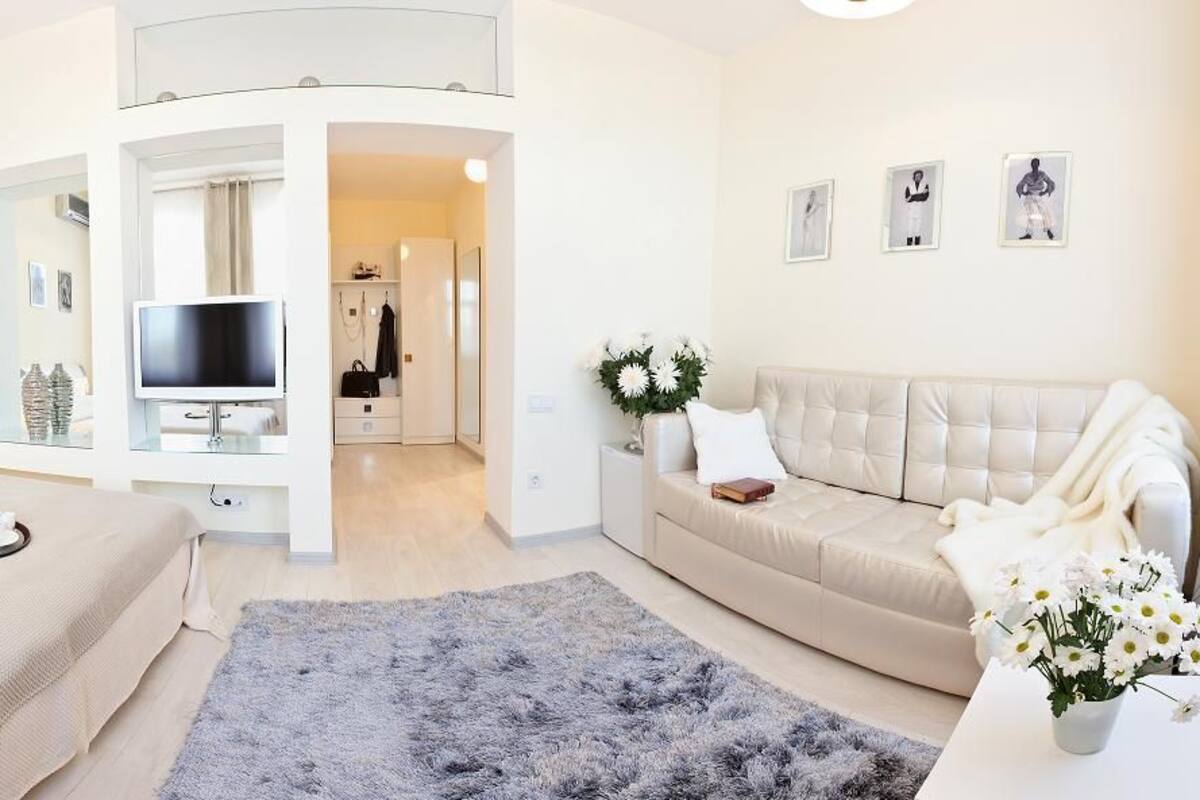 Quarto de hotel moderno com cama, sofá, televisão e escrivaninha.