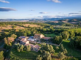 Vista aérea de uma propriedade rural com construções de pedra, piscina e vegetação ao redor.