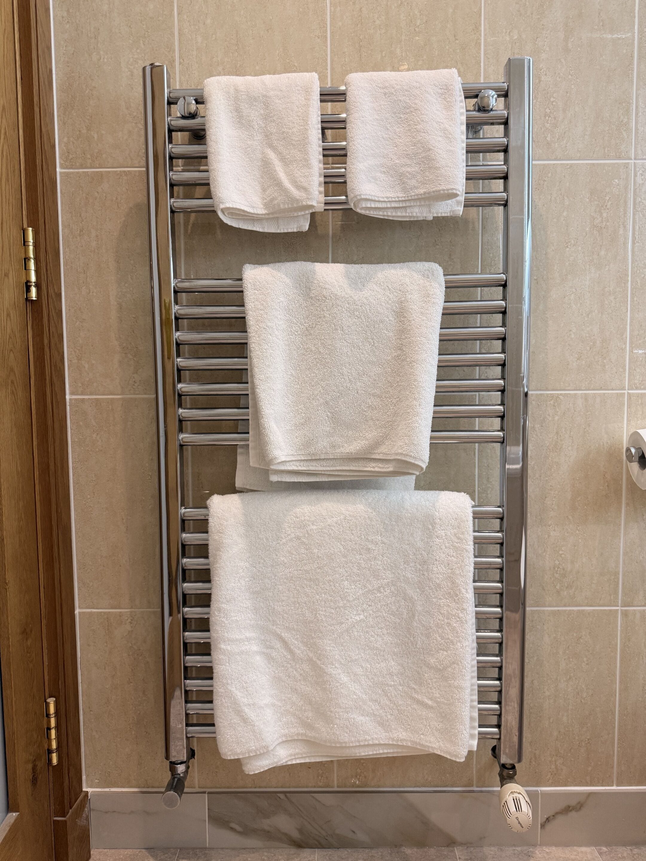 Casa de banho com um porta-toalhas com três toalhas brancas.