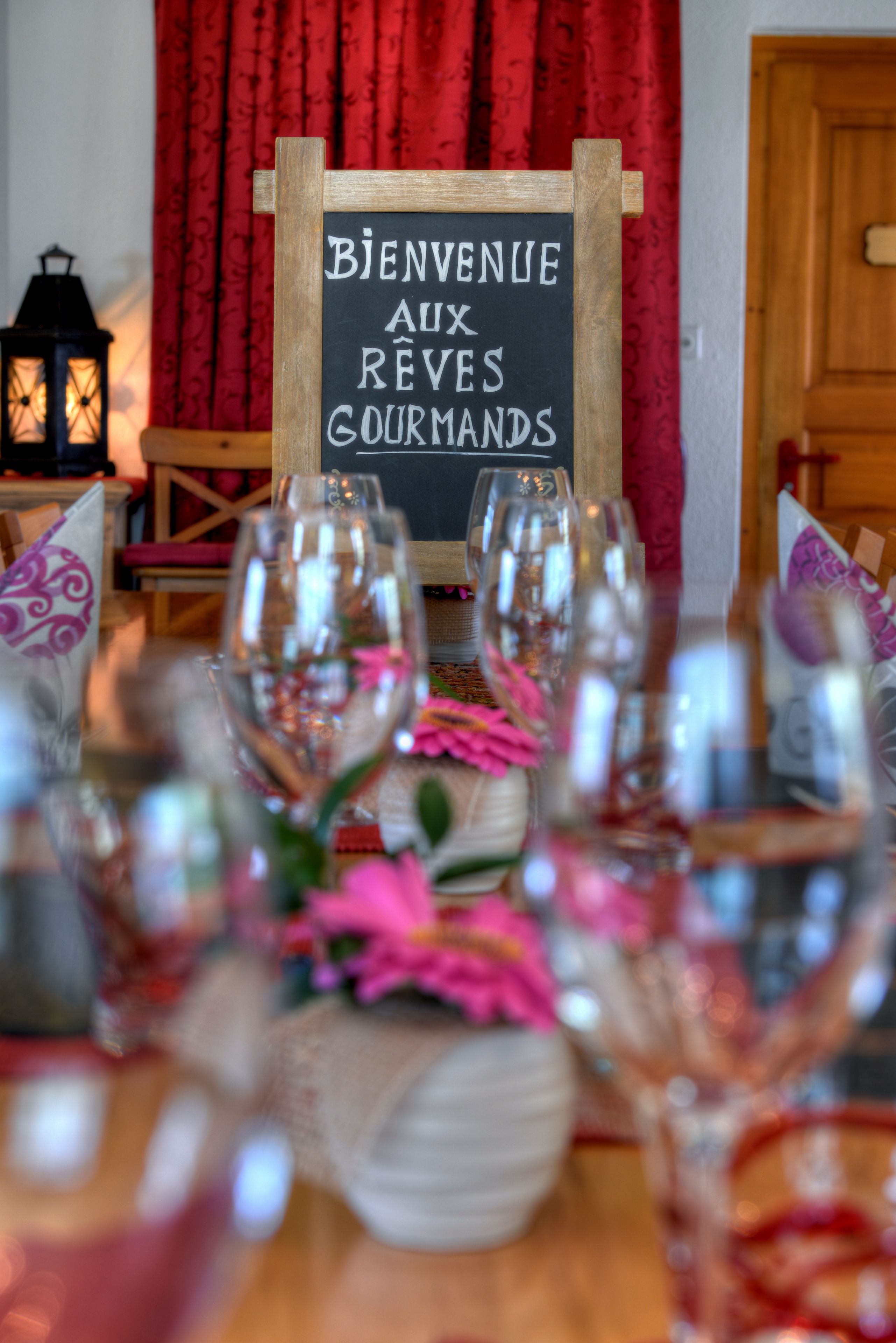 Mesa posta com taças de vinho e um letreiro que diz "Bienvenue aux Rêves Gourmands".