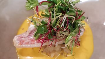 Prato com carne, vegetais e molho amarelo.