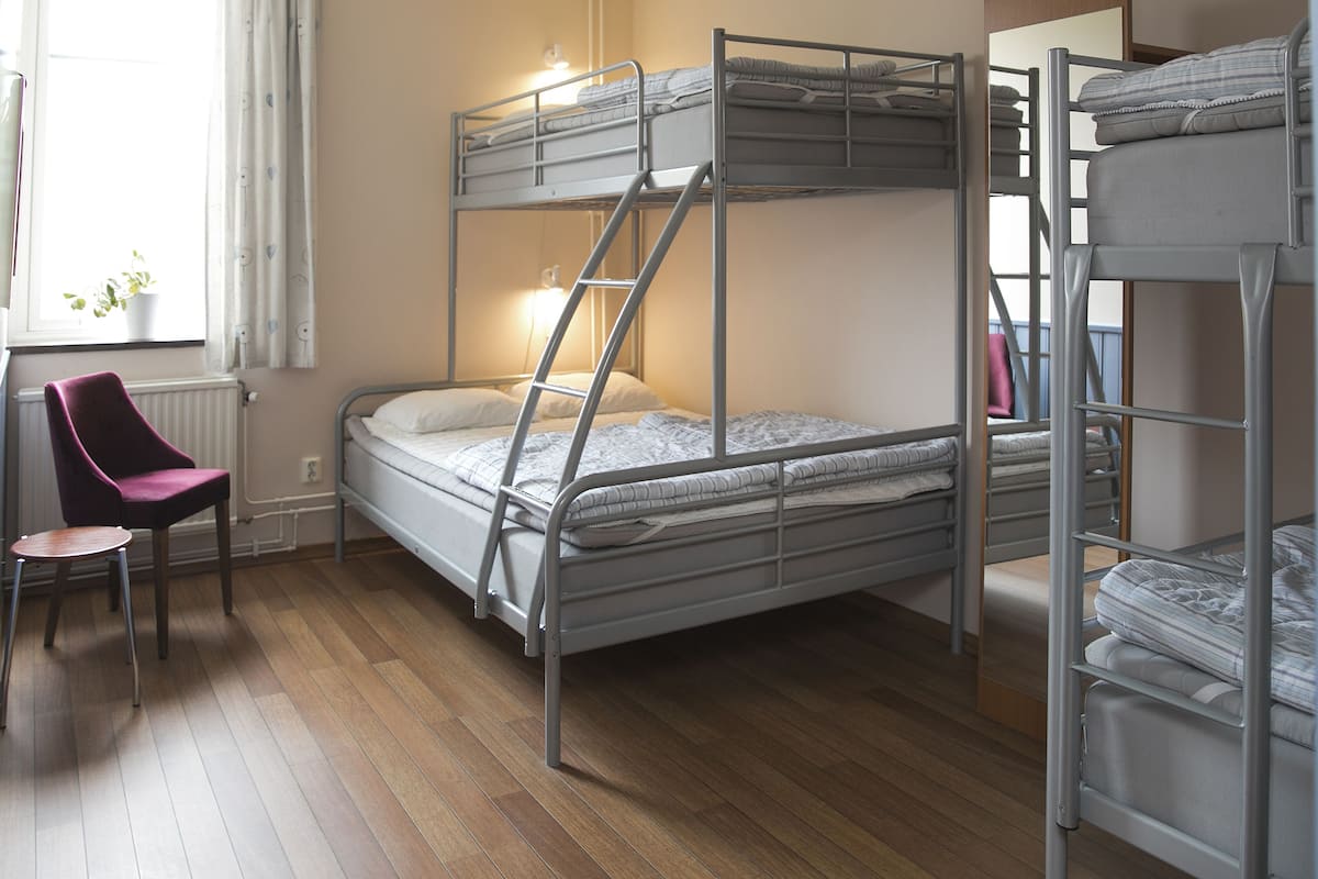 Quarto com beliche, uma cadeira e radiador.