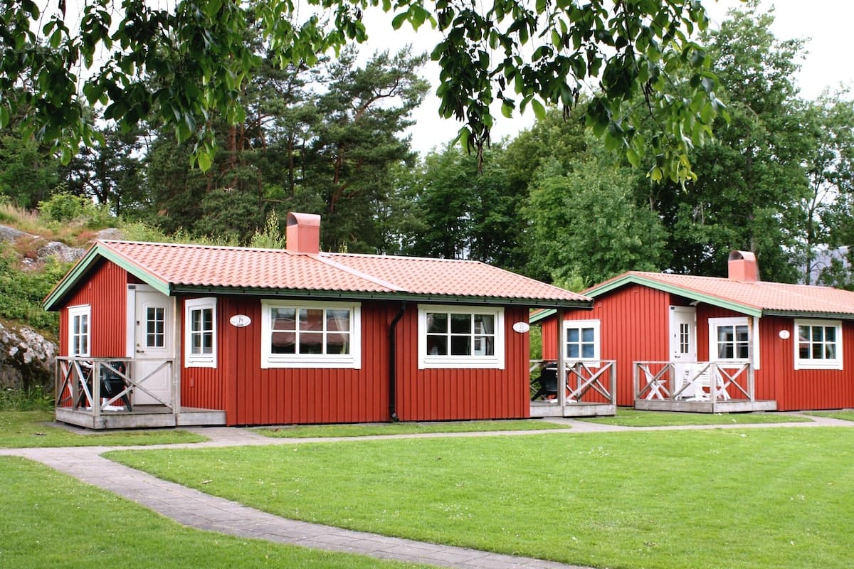 Um edifício vermelho com telhado vermelho, janelas brancas e varanda com grade.